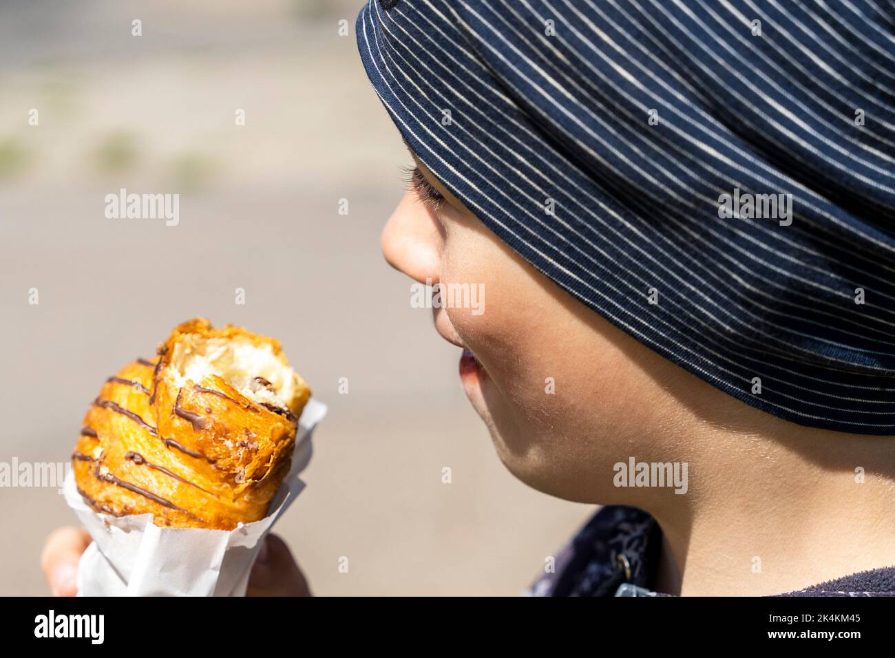a cheerful cheerful boy is eating a bun on the street Stock Photo - Alamy