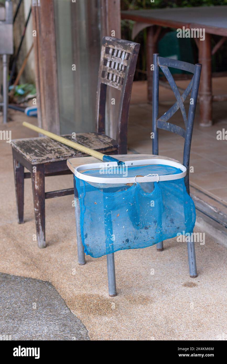 The net for cleaning pool from leaves lies on old chairs. Vertical ...