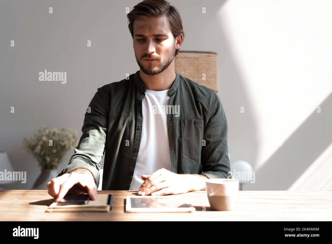 Young employee at workplace using mobile phone, checking social media ...