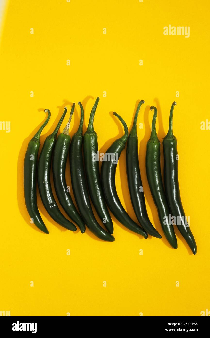 A vertical view of a bunch of green hot chili peppers in the yellow ...
