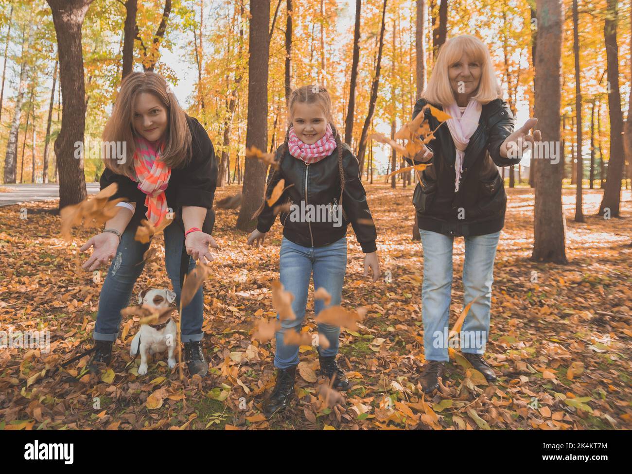 Grandmother and mother with granddaughter throw up fall leaves in ...