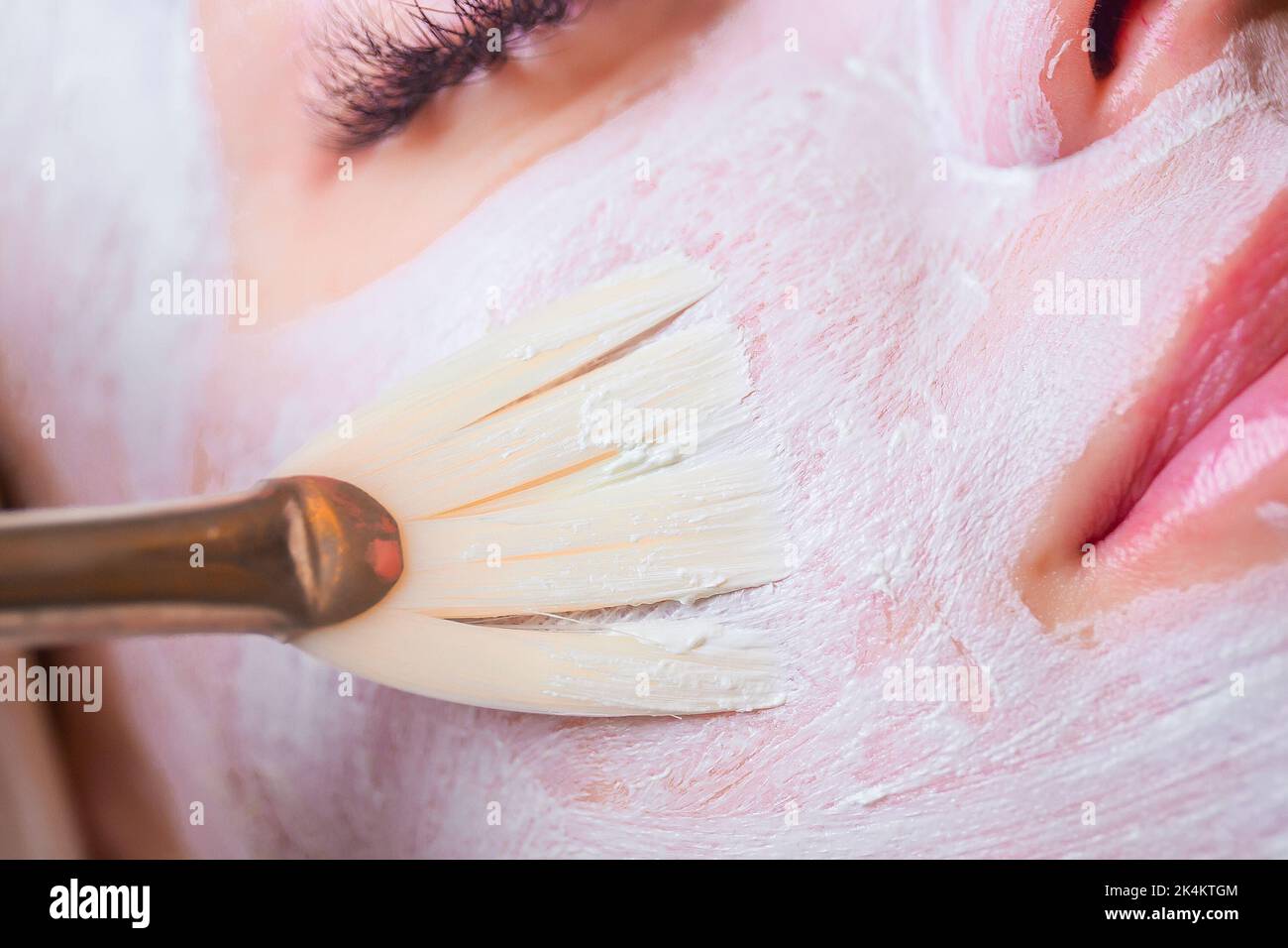 A closeup of a brush applying cream to a woman's face. Facial peeling ...