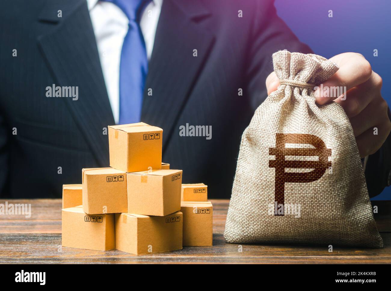 Businessman holds philippine peso money bag and boxes with goods ...