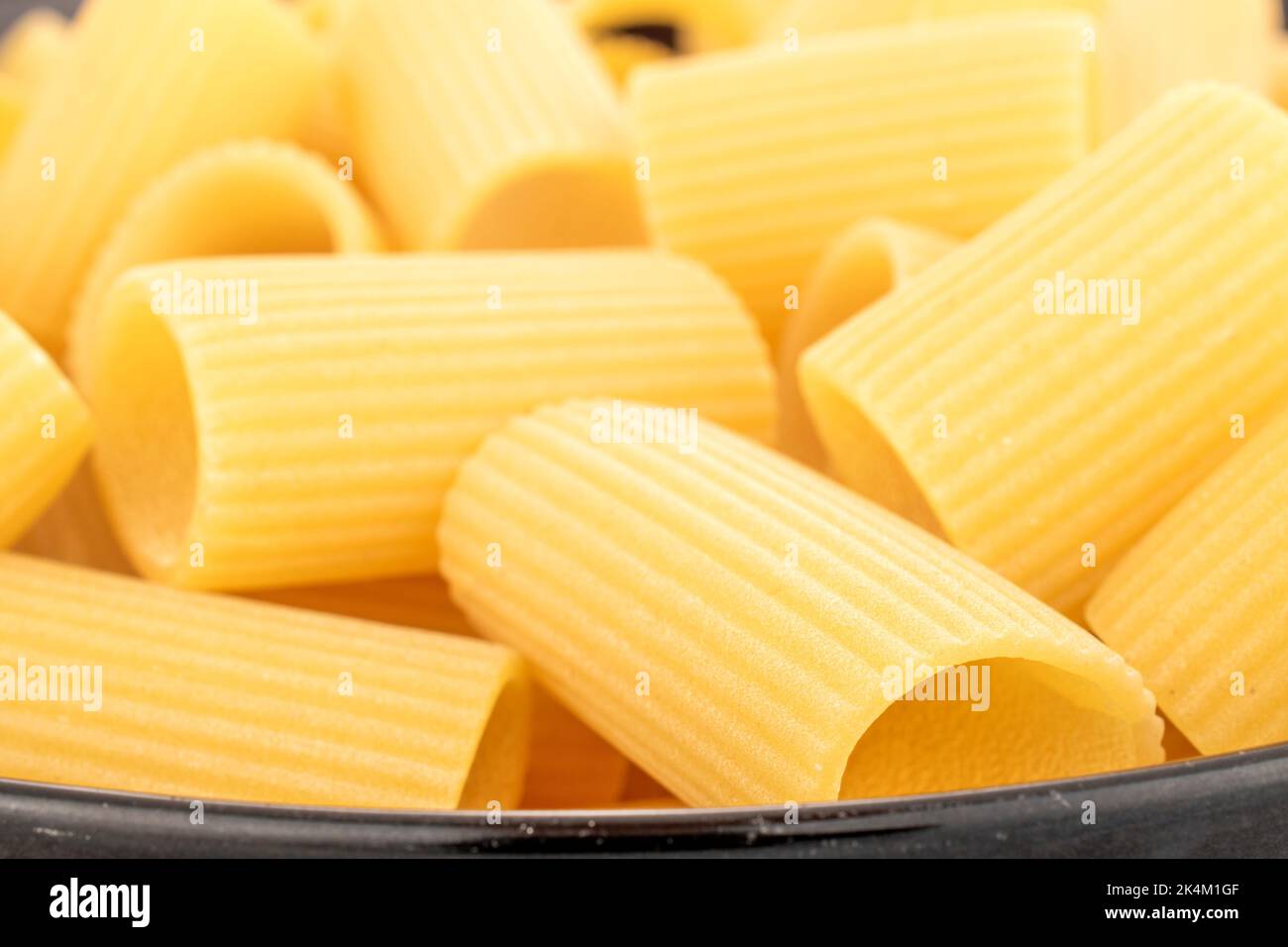 Several raw yellow cannelloni in a black ceramic plate, macro Stock ...