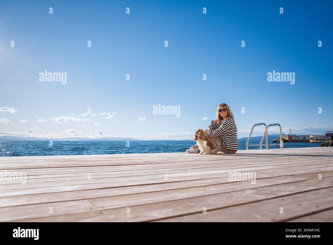 Shot of a happy woman wearing striped sweater while sitting with her ...