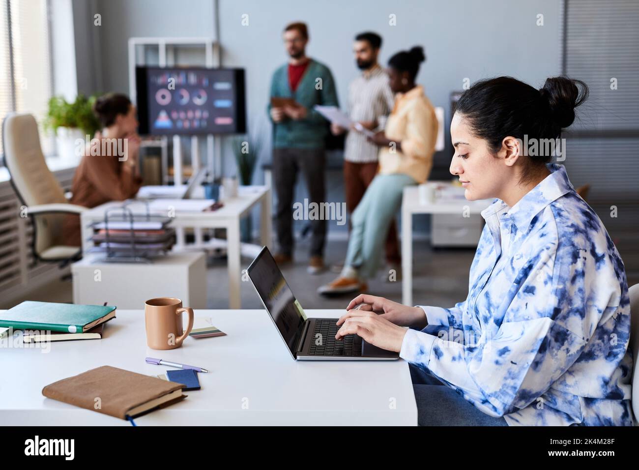 Side view of young serious female employee typing on laptop keypad ...