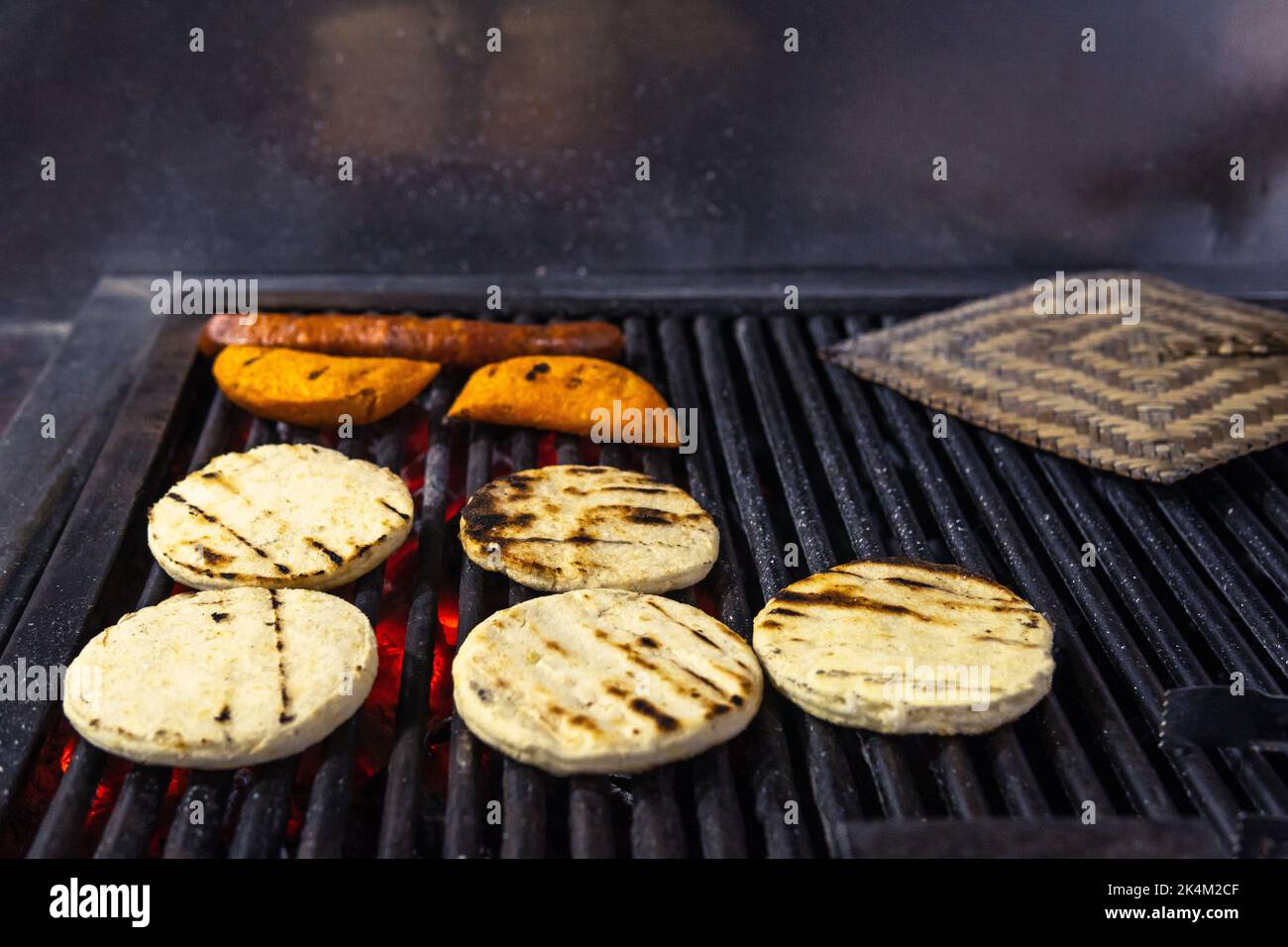 Grill with arepas, empanadas and chorizo next to a fan. traditional ...