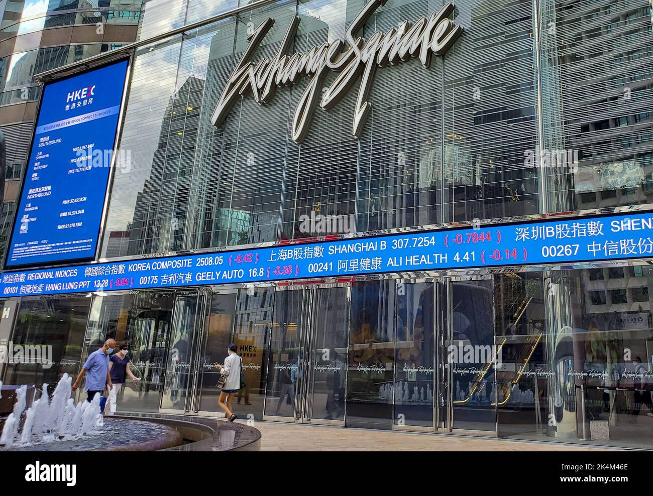 People walk past signage for Hong Kong Exchanges & Clearing Ltd. (HKEX) displayed at the ...