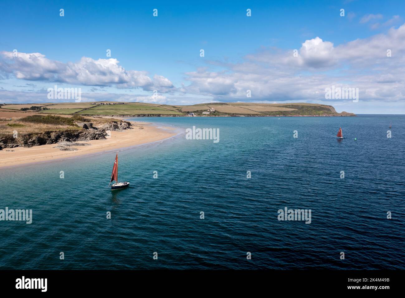 An old fashioned sailing boat with a red sail floating on the ocean in ...