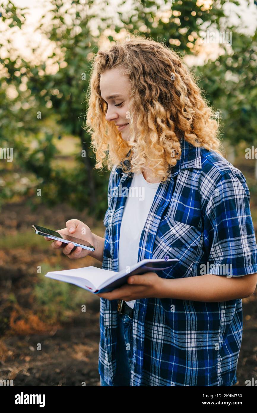 Woman farmer using computer in cornfield making notes and using a ...