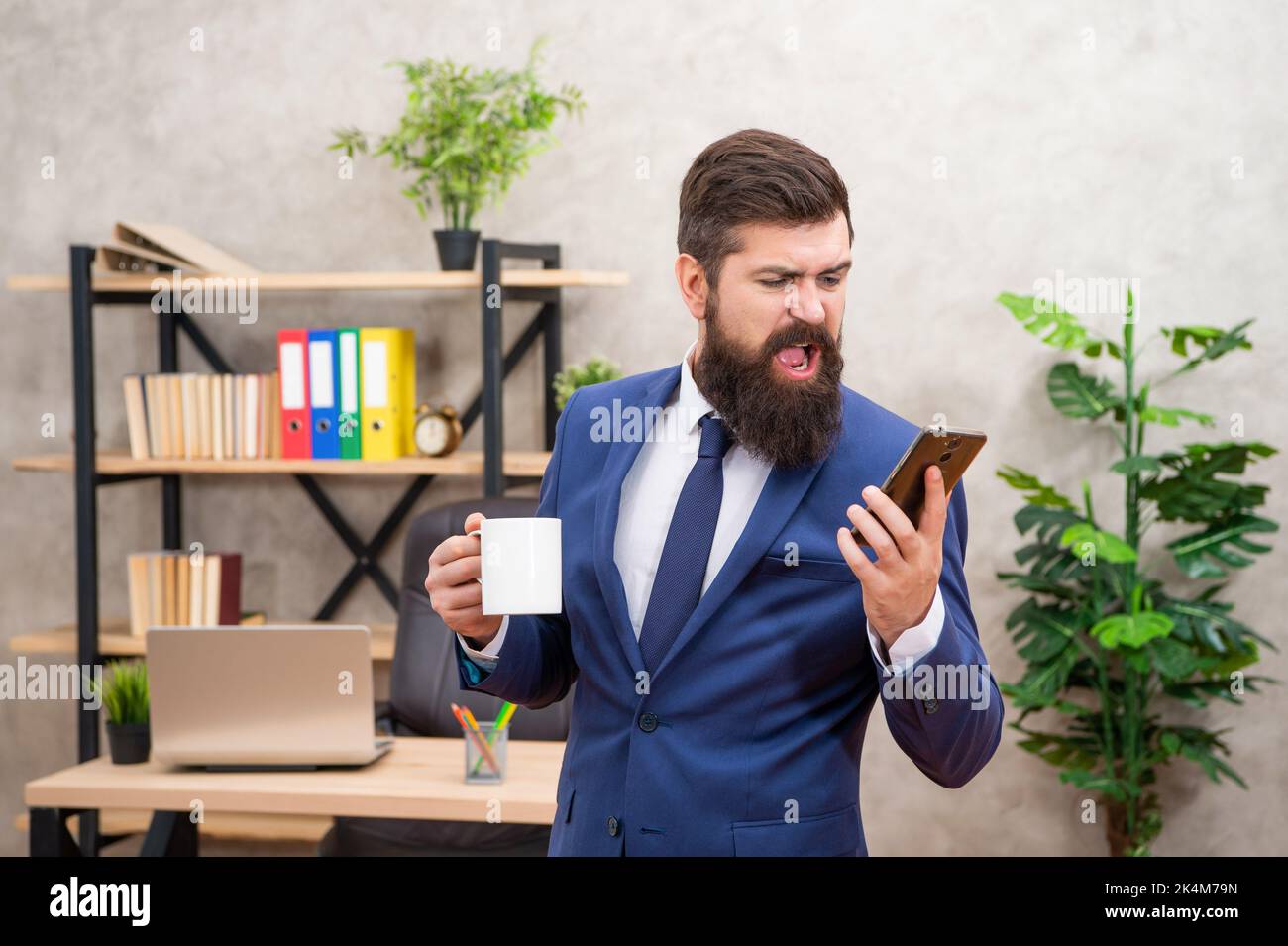 Stressed boss yelling in anger while talking on mobile phone in office ...