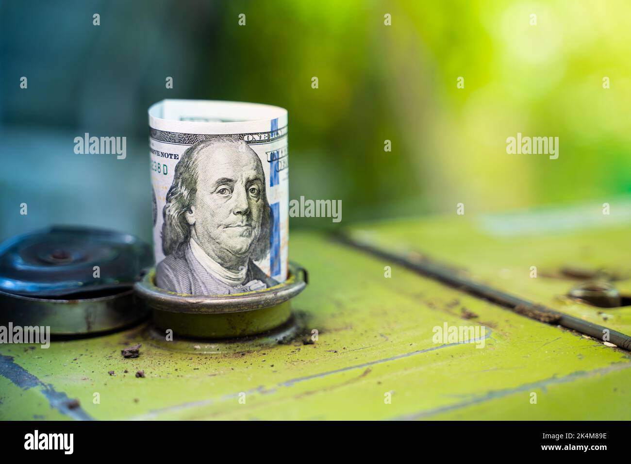 A hundred dollar bill is twisted into a tube sticking out of the gas ...