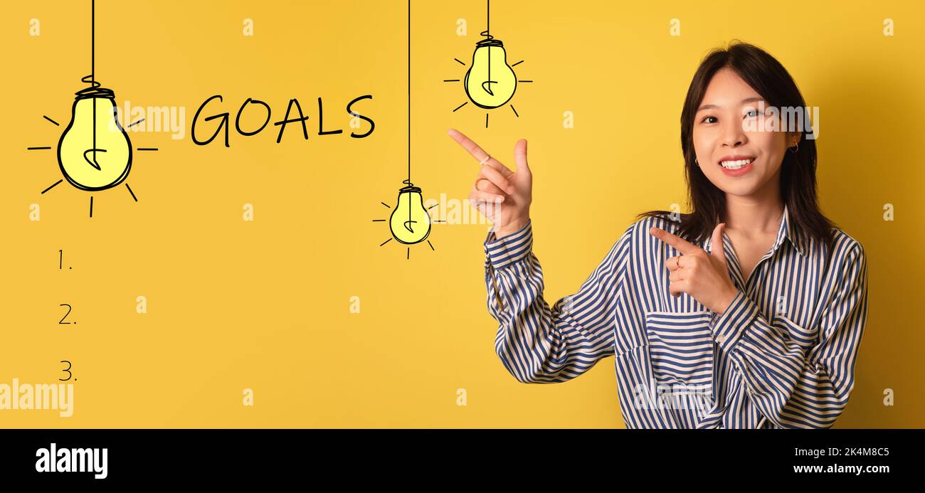Smiling adult asian woman point finger at goals inscription with light ...