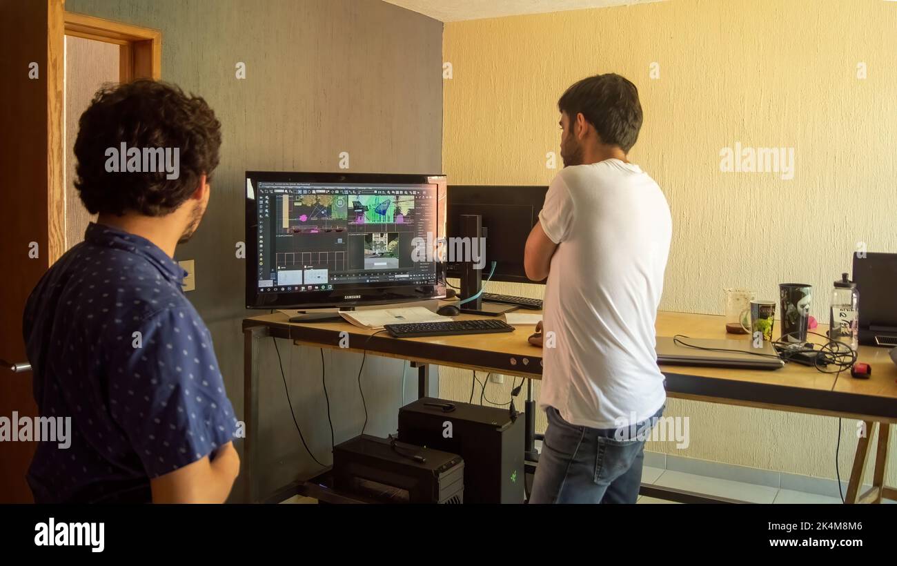 two young architects reviewing the plans and the project on a monitor ...