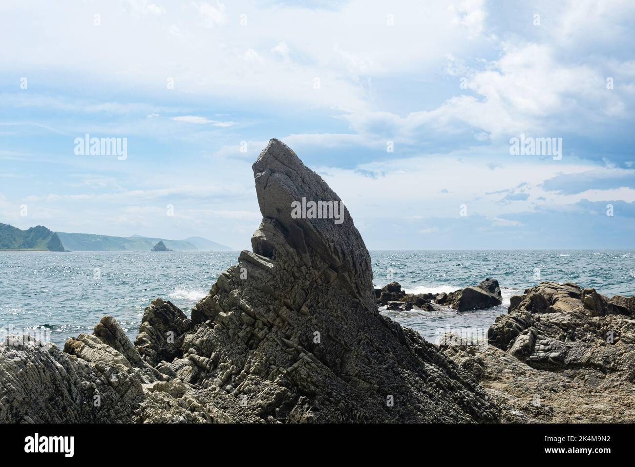 rocks formed by solidified lava against a blurred coastal seascape ...