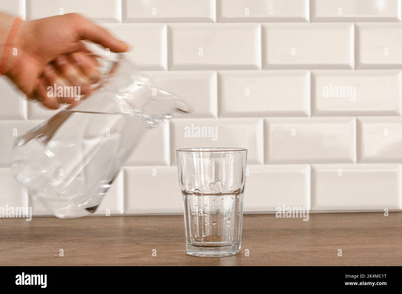 An empty glass water glass stands on a wooden table against a white ...