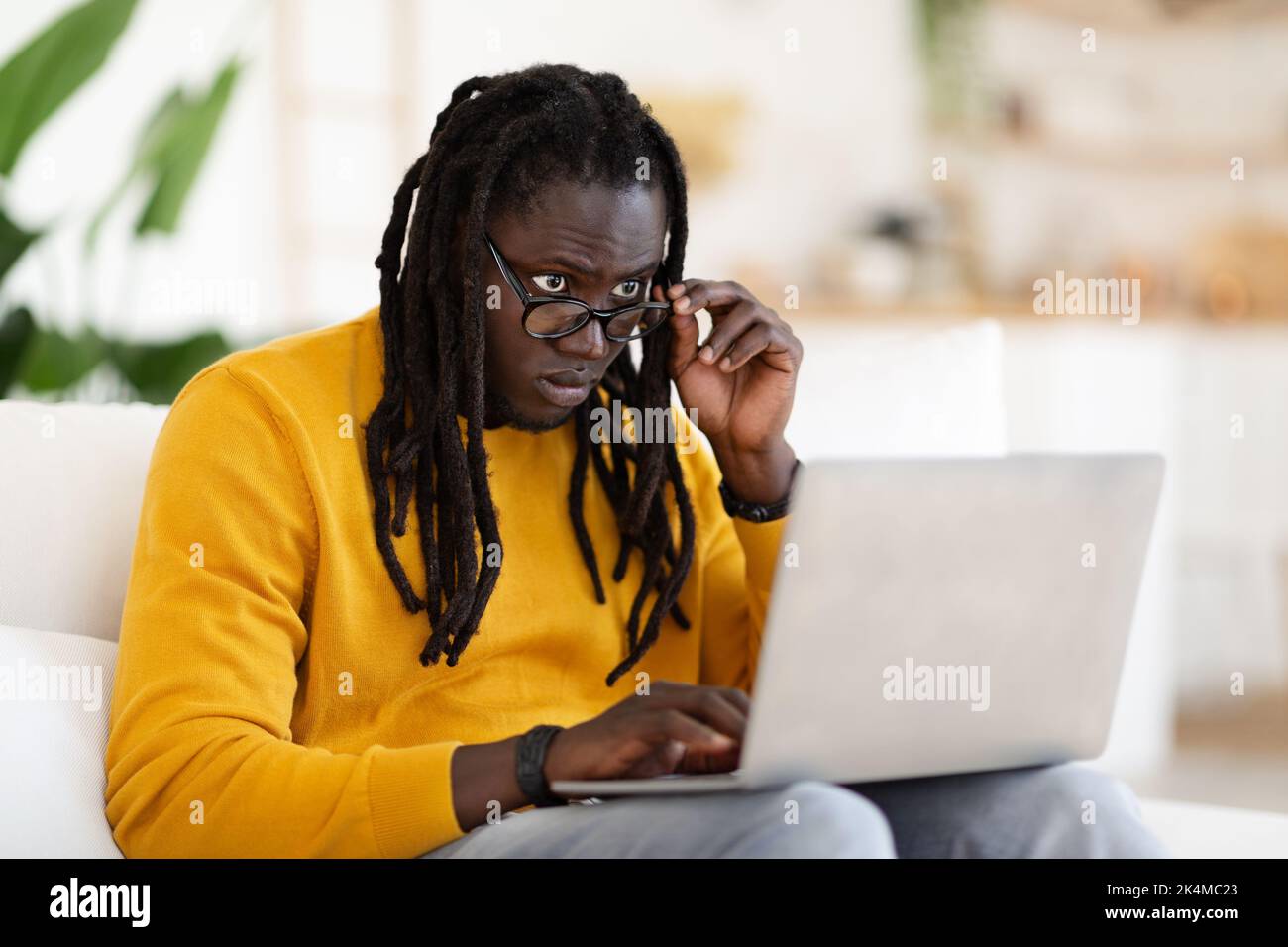 Confused Black Man Looking At Laptop Screen While Using Computer At Home Stock Photo - Alamy