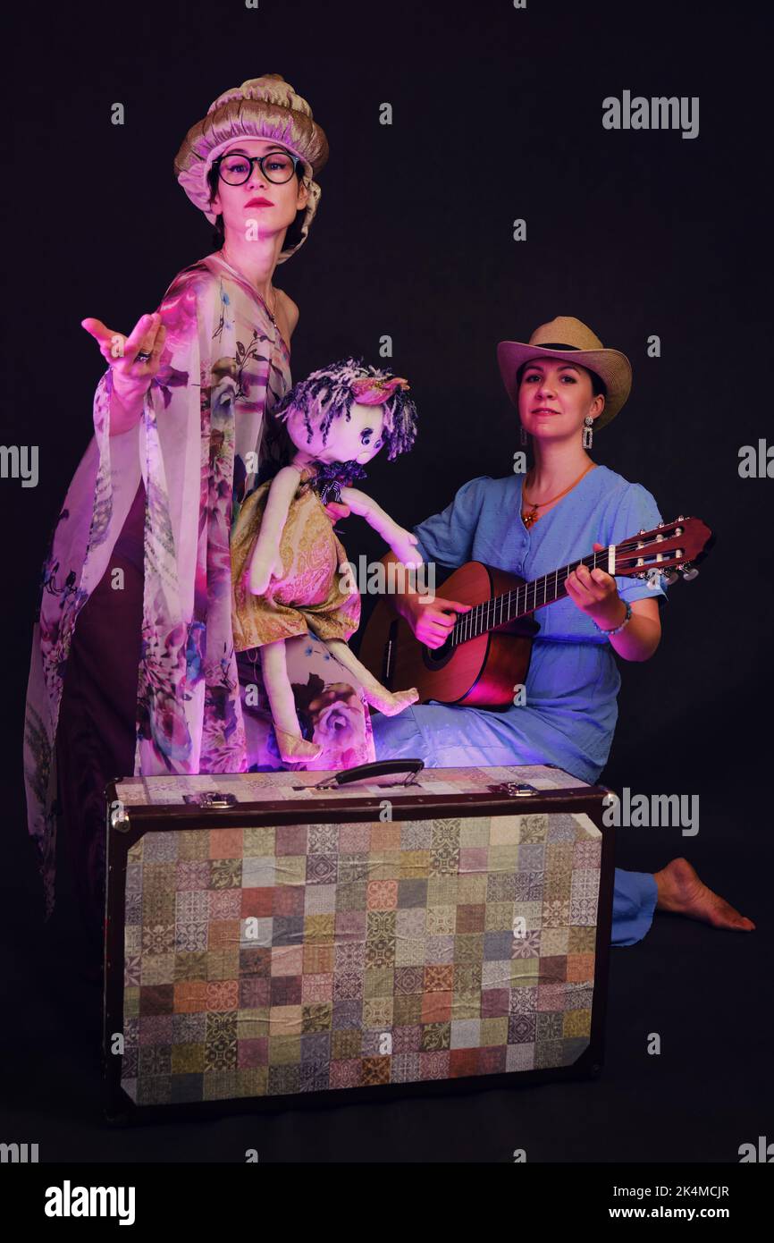 Happy women in funny wigs give a musical performance on a studio black ...