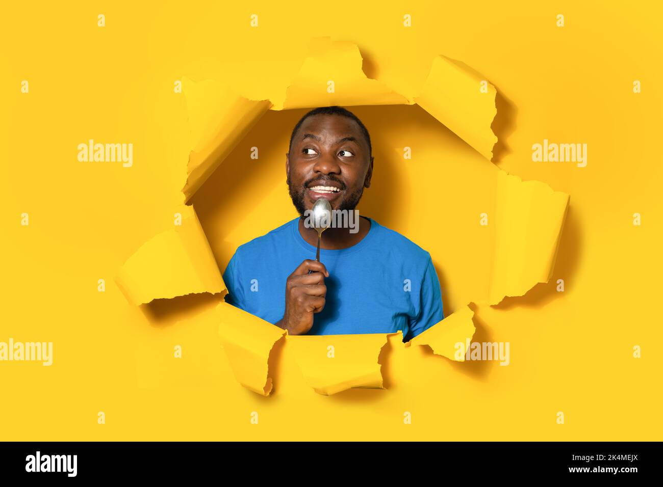 Hungry african american man with spoon in his mouth looking at copy ...