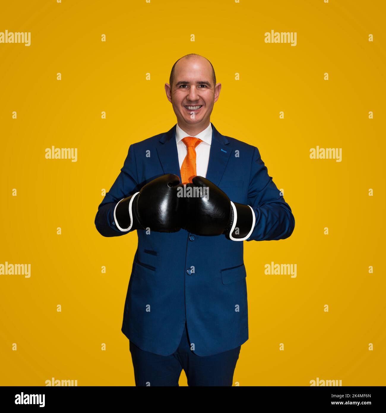 A bald Caucasian adult male wearing a blue suit, white shirt and orange ...