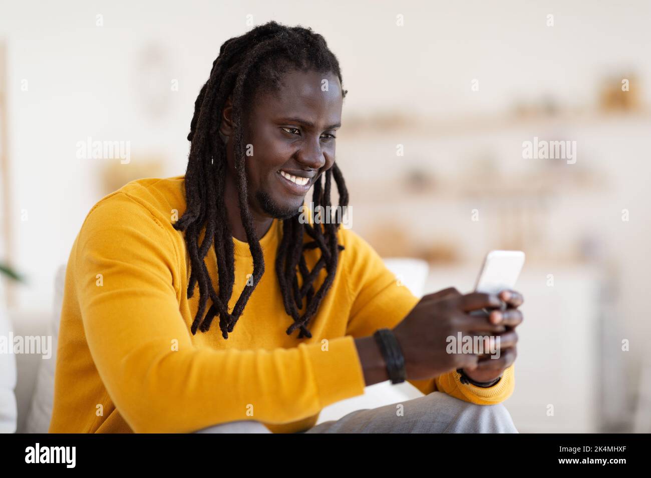 Cheerful Black Man Messaging On Mobile Phone While Relaxing At Home ...