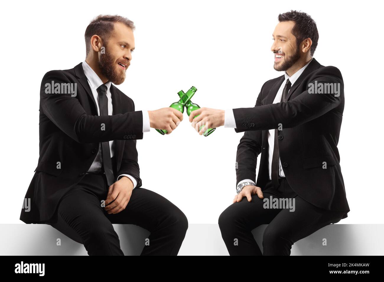 Businessmen sitting on a blank panel and toasting with bottles of beer ...