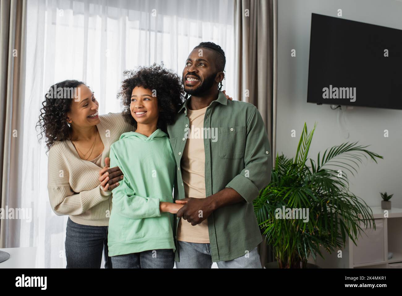smiling african american parents hugging cheerful preteen daughter at ...