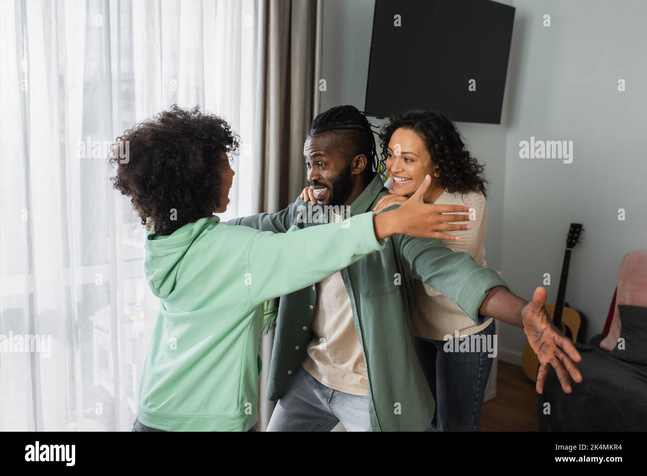 happy african american girl hugging cheerful parents at home,stock ...