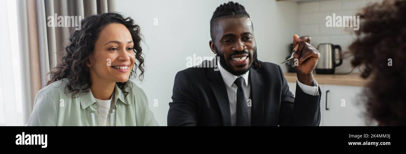 cheerful african american parents looking at curly daughter, banner ...