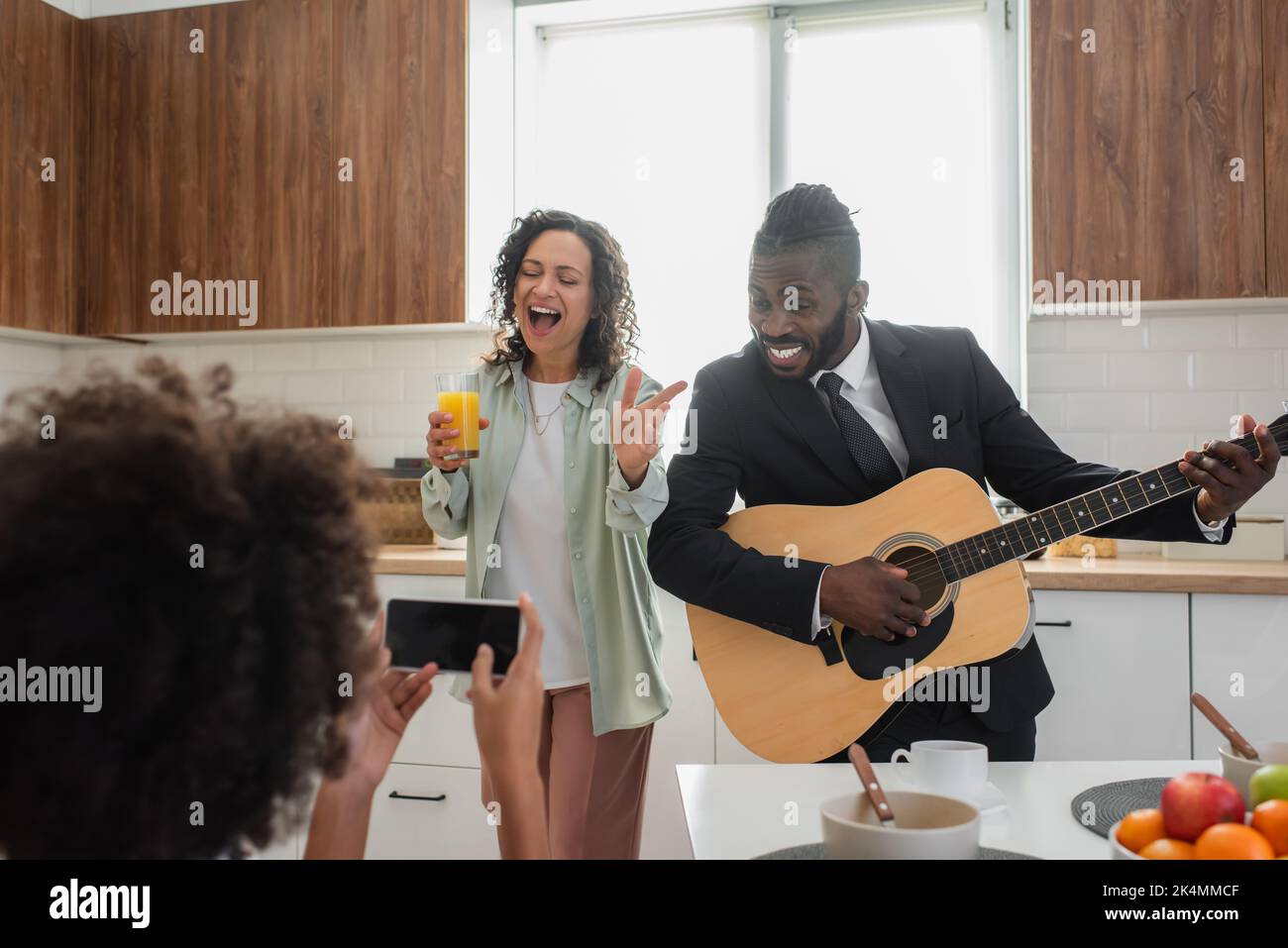 curly african american kid taking photo of happy father in suit playing ...