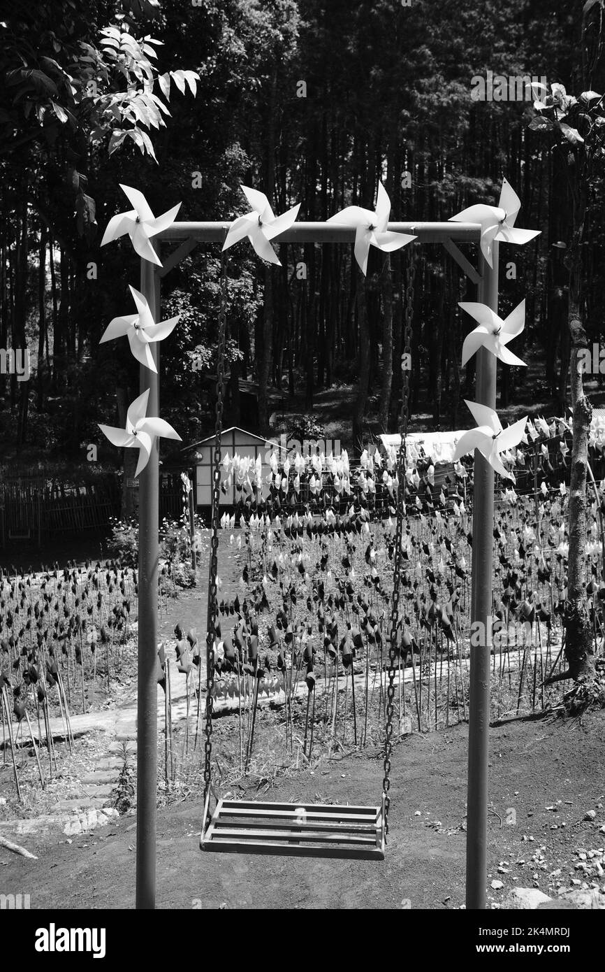 Black and white photo of swings on a playground decorated with a ...