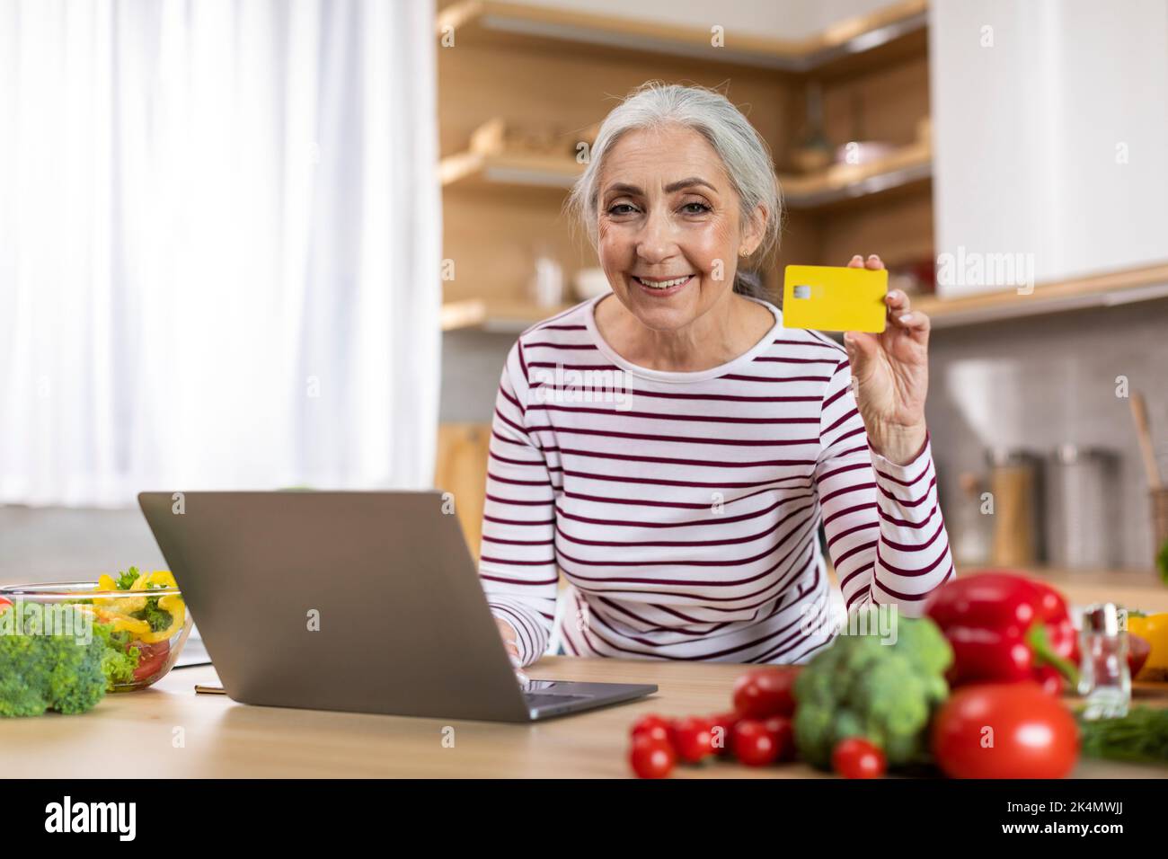 E-Commerce. Senior Woman With Laptop And Credit Card Posing In Kitchen ...