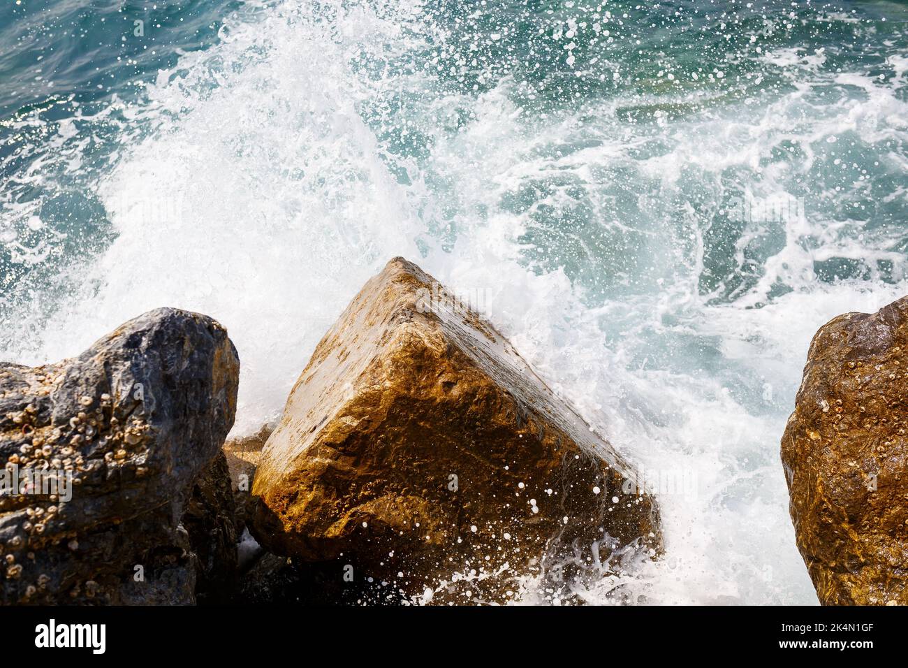 Sea water beats against rocky rocks and makes waves with foam, rugged ...
