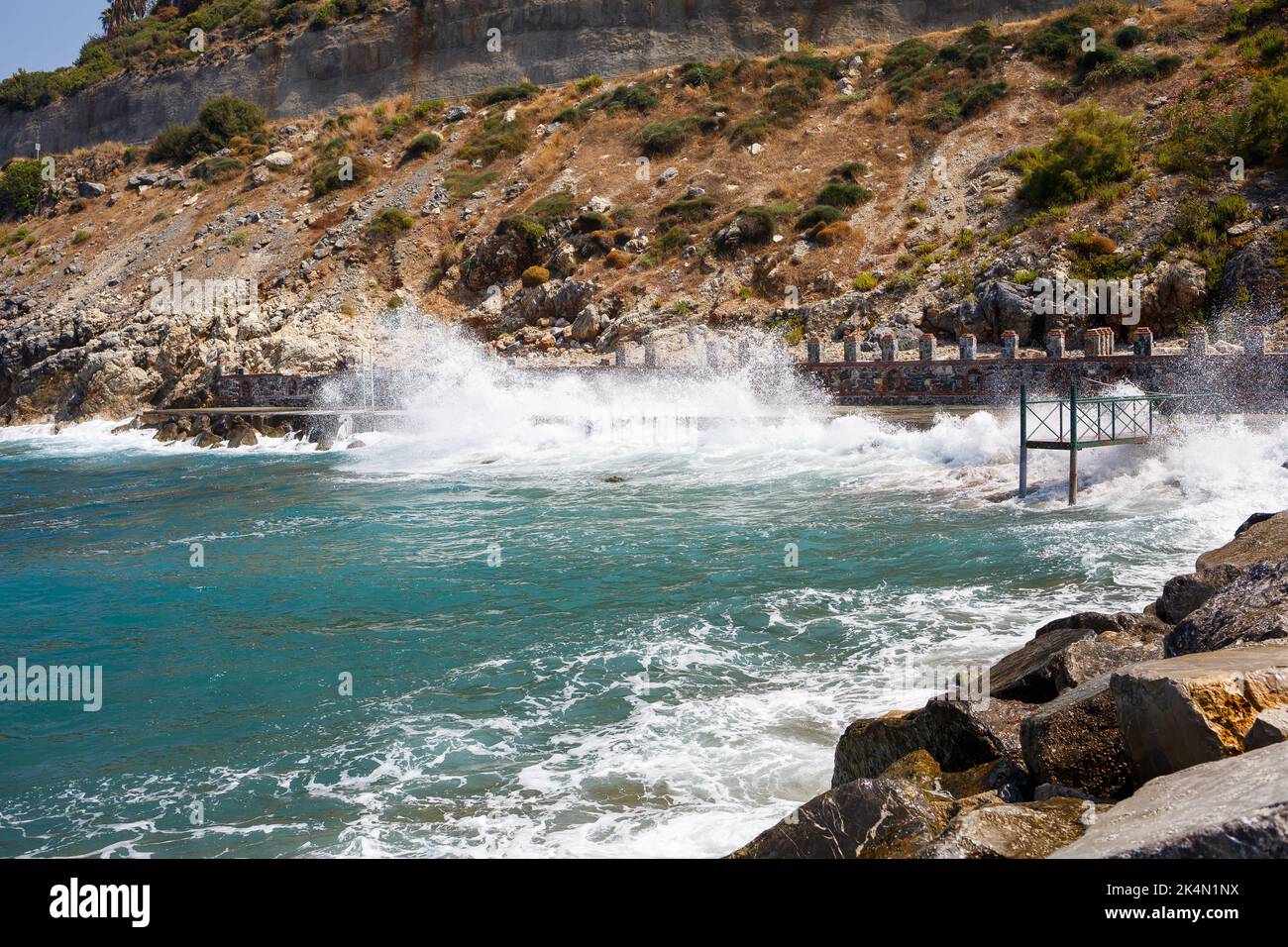 Sea water beats against rocky rocks and makes waves with foam, rugged ...