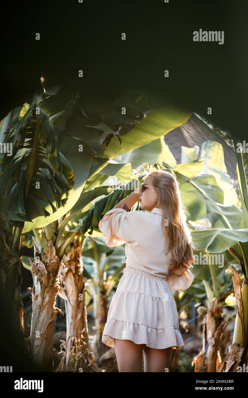 Exotic tropical woman near green leaves of banana bush. Tropical island ...