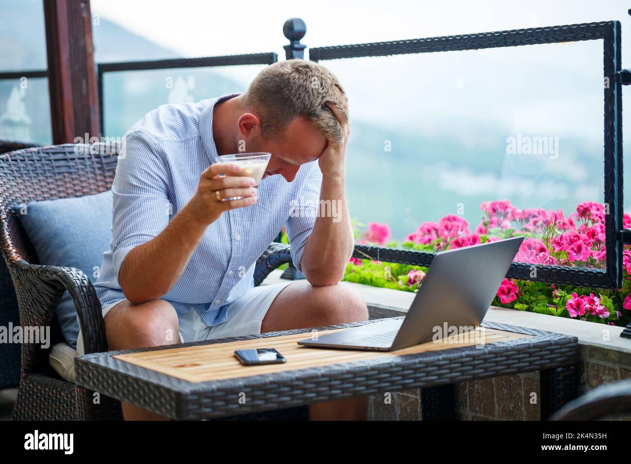 An emotional man sits at the computer on vacation and works. Freelancer ...