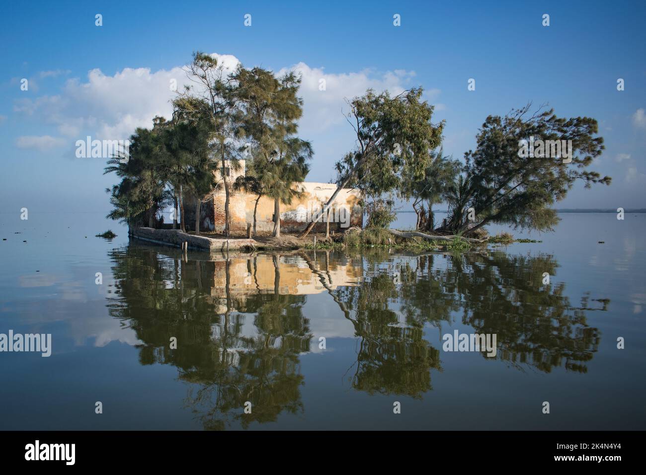 A scenic shot of a building on a small island surrounded by trees ...