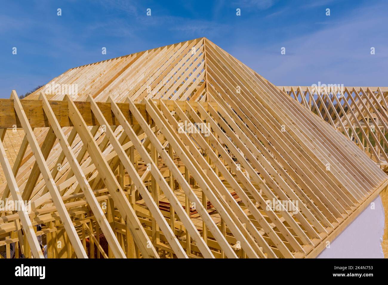 As roof beam of a new house is being constructed from wooden trusses ...