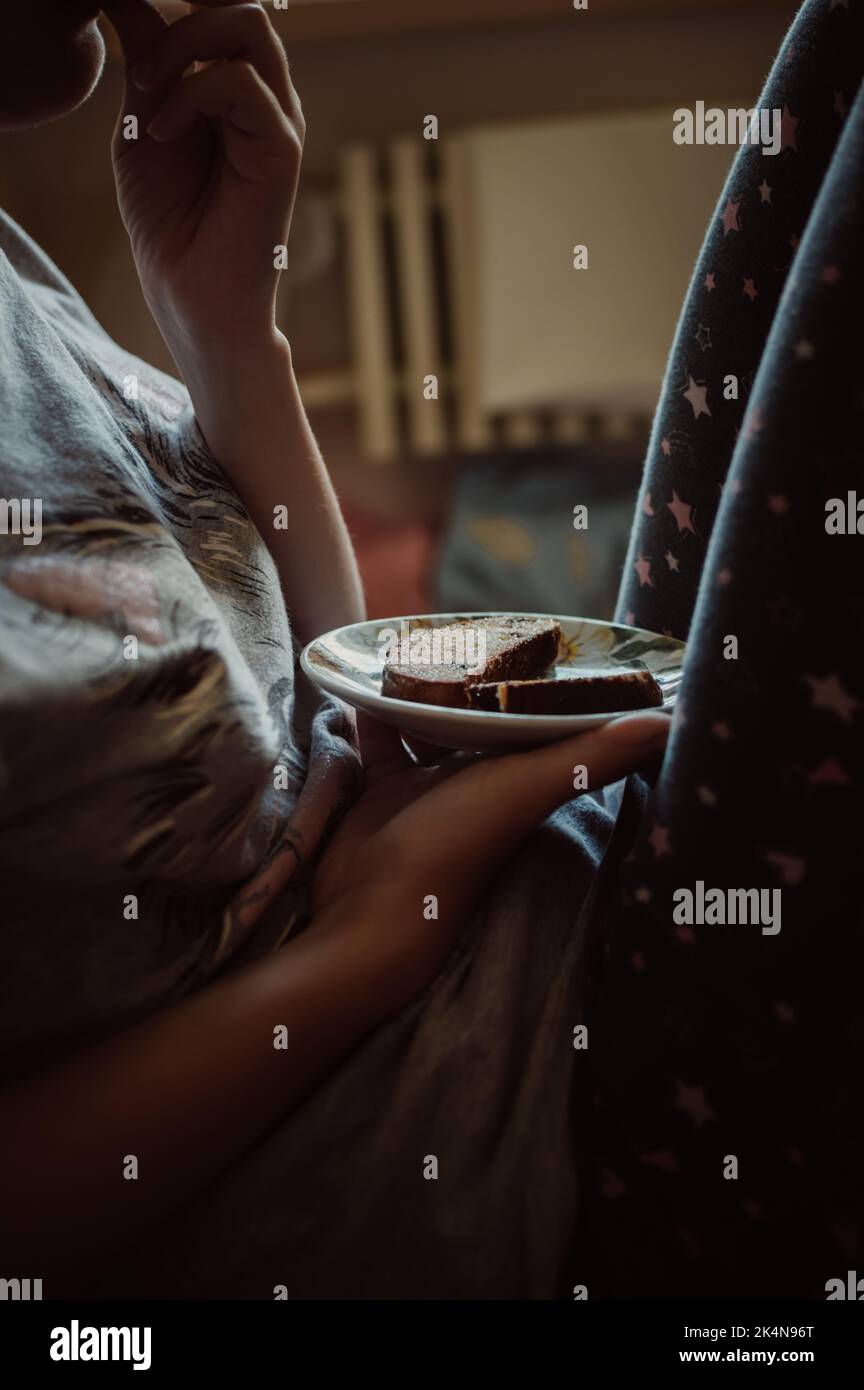 Girl eats crackers at home, feet drawn up Stock Photo - Alamy