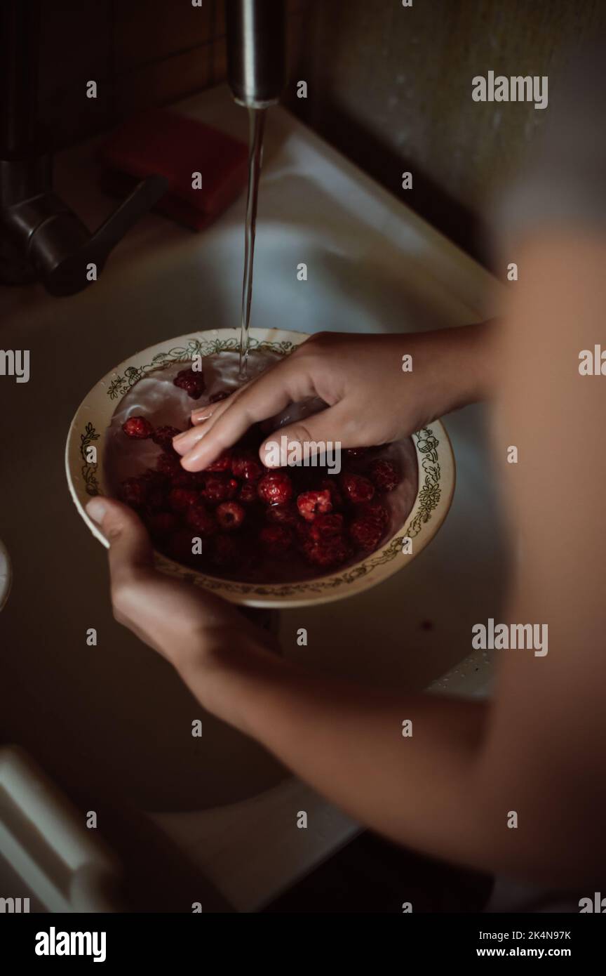 Hands washing red raspberries on plate under running water Stock Photo ...