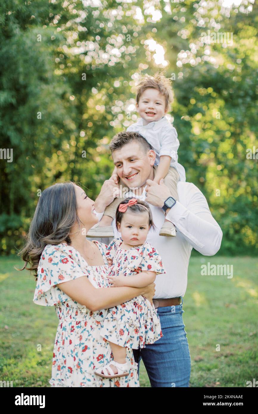 Multiracial parents hold their two young children and smile Stock Photo ...