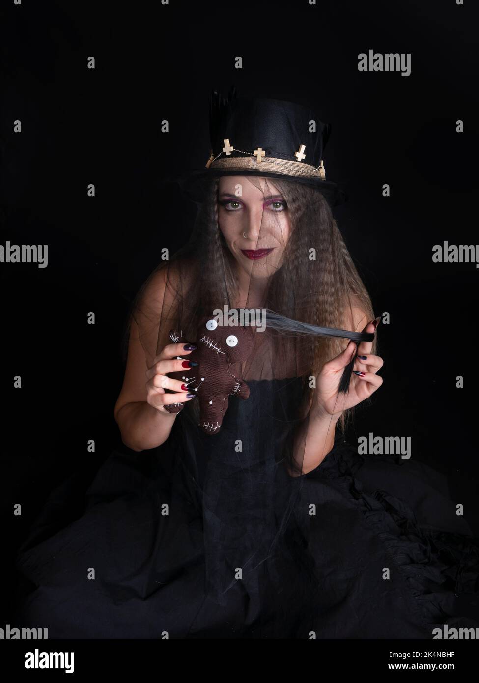 Woman looking at camera and sticking a needle into a voodoo doll Stock ...