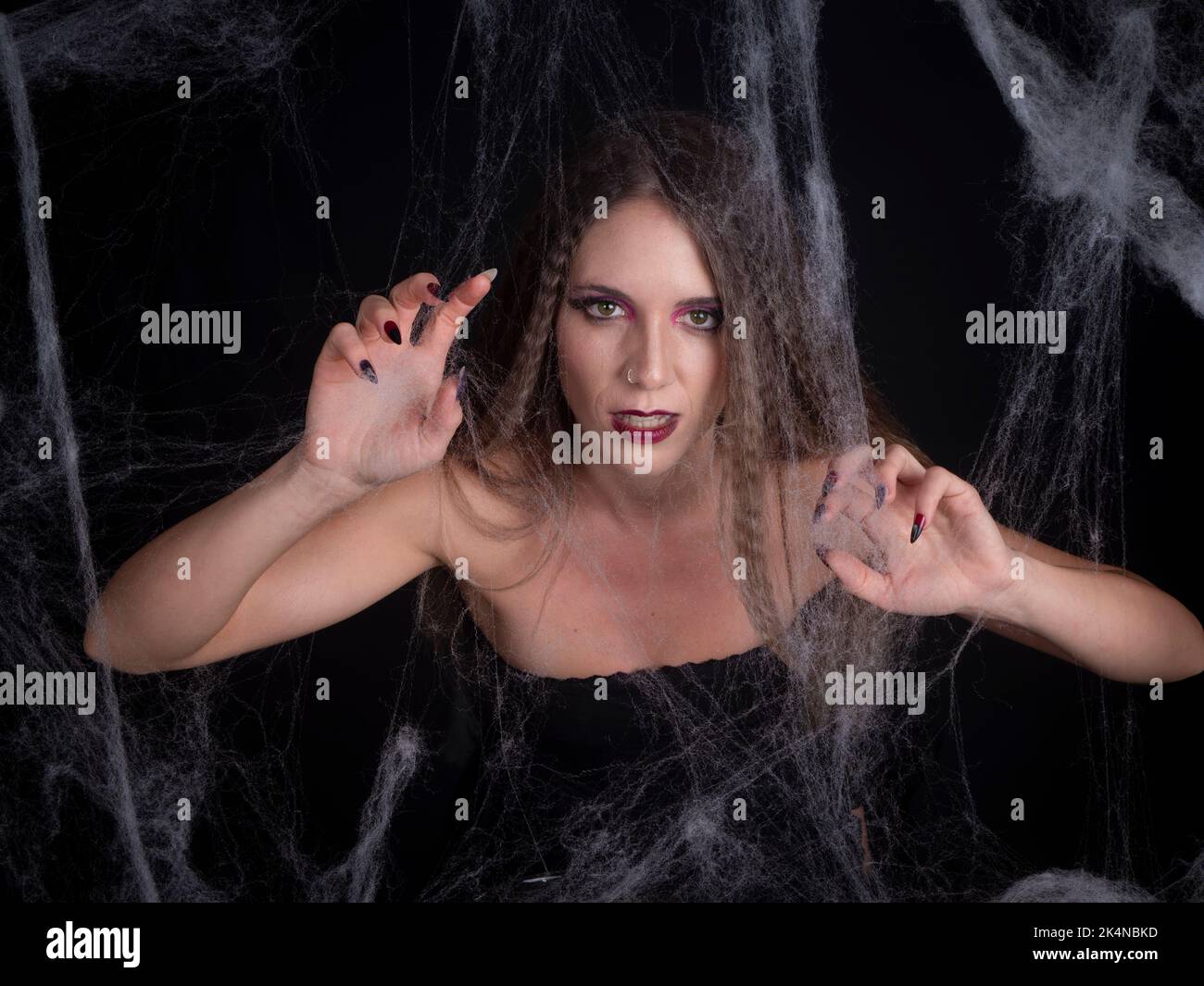 Woman casting a spell between spider webs Stock Photo - Alamy