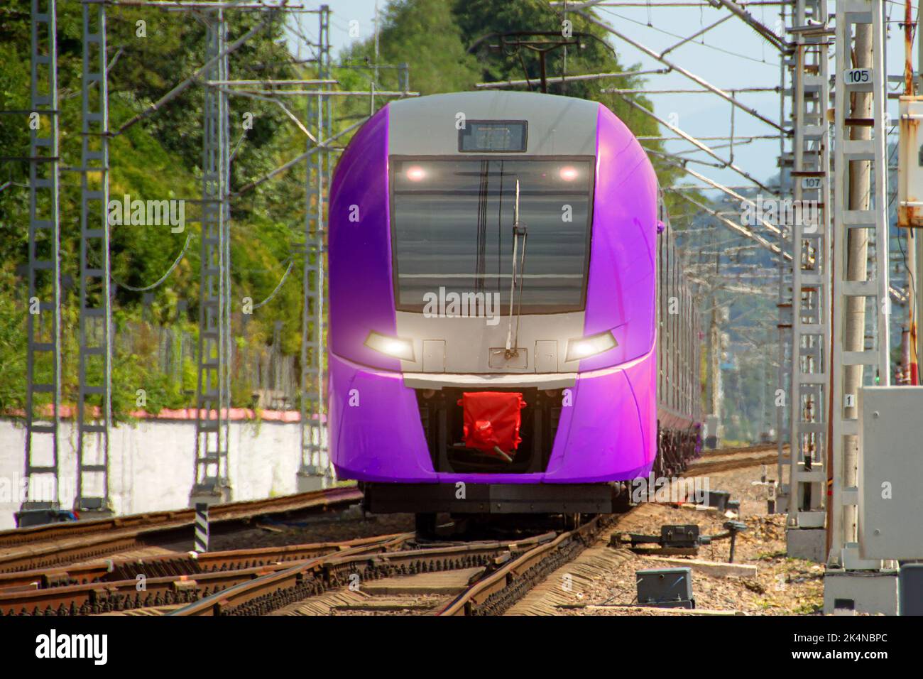 Passenger lilac violet electric train departs from the station platform ...