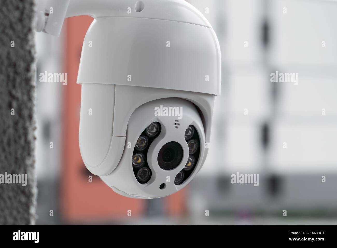 Modern CCTV camera on a wall with a blurred multi-storey building on ...