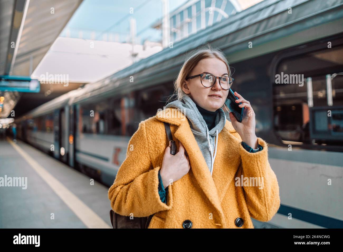 Caucasian serious woman calling by phone waiting on station platform on ...