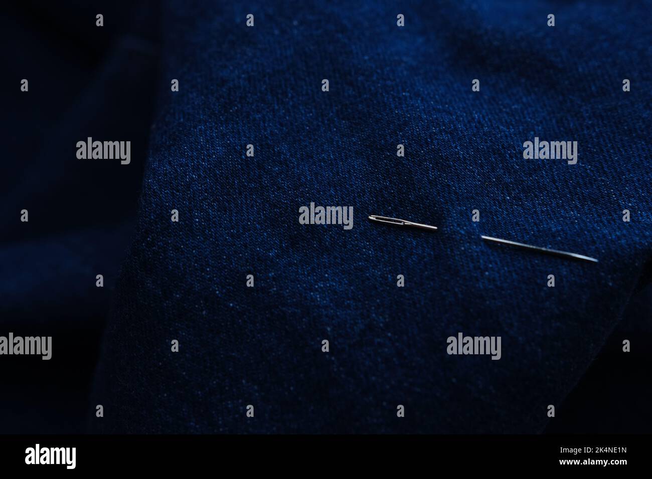 Sewing thread and needle at jeans denim background texture. Tailor ...