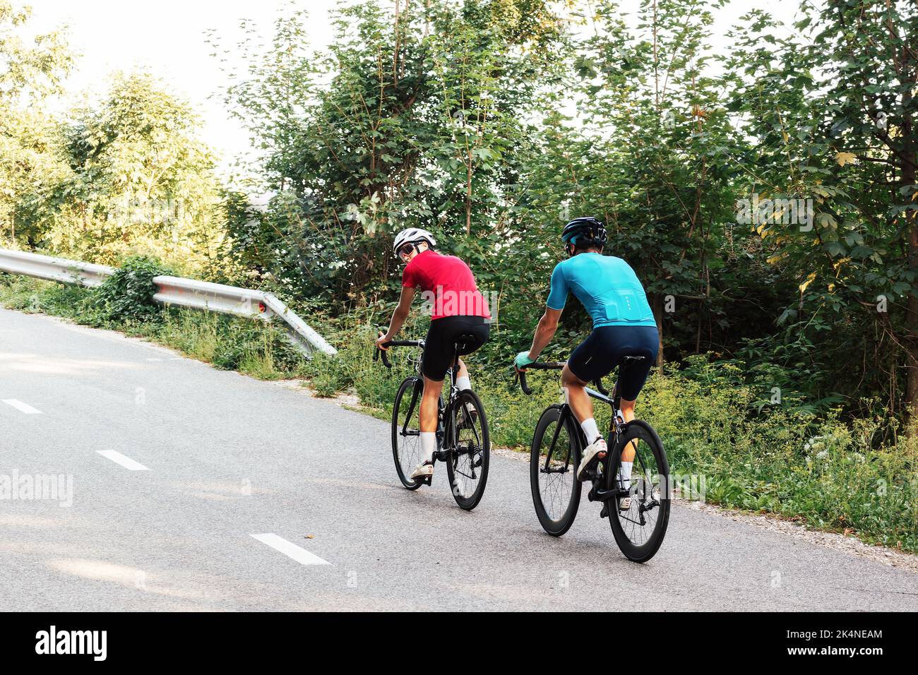 Female athlete on a racing bicycle riding uphill an asphalt road at ...