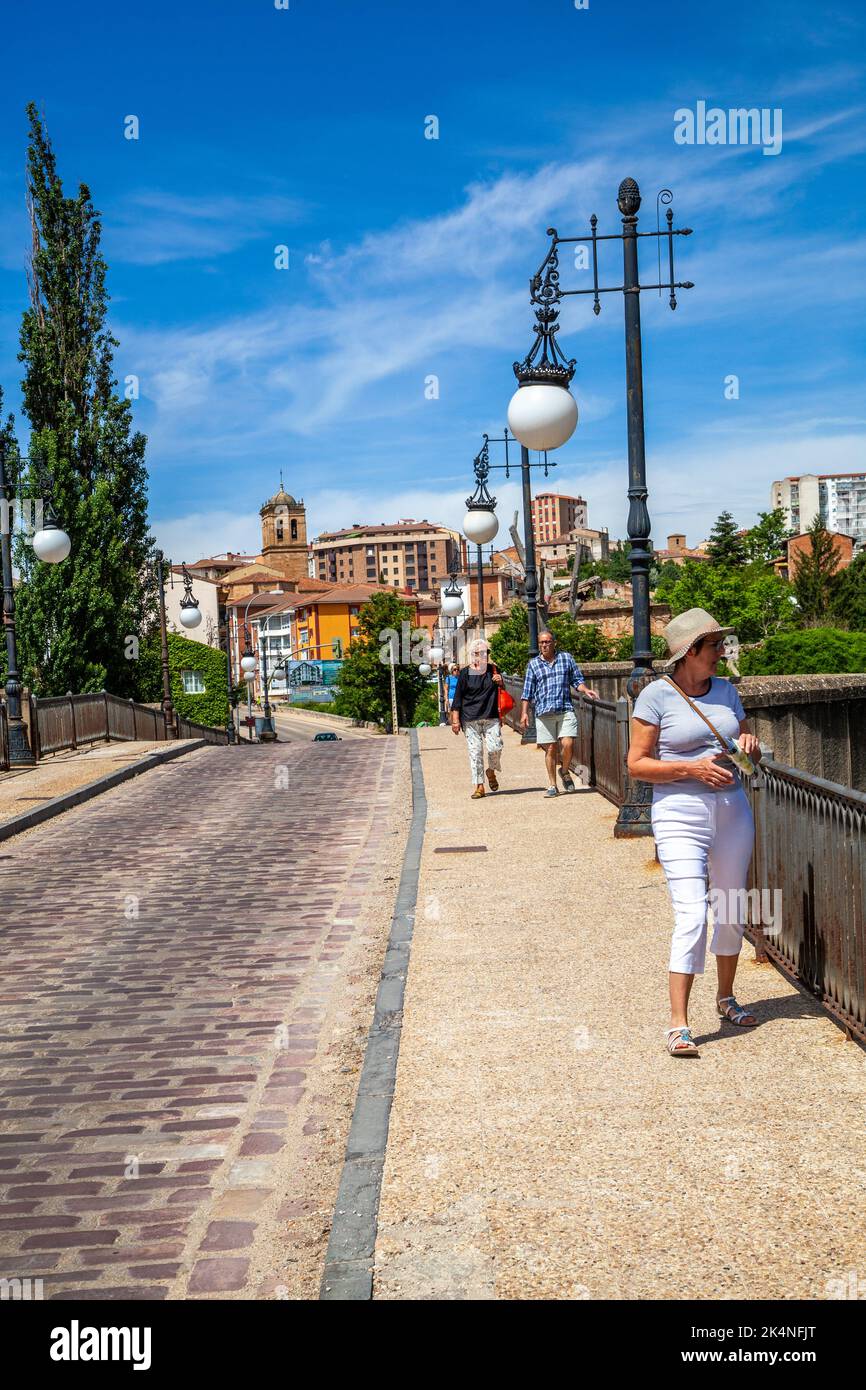 People walking along the medieval bridge over the river Rio Duero in ...