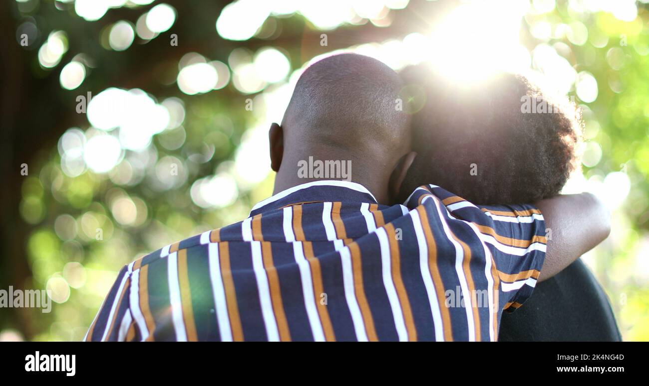 Back of African couple embracing outside in sunlight. Husband hugs wife ...